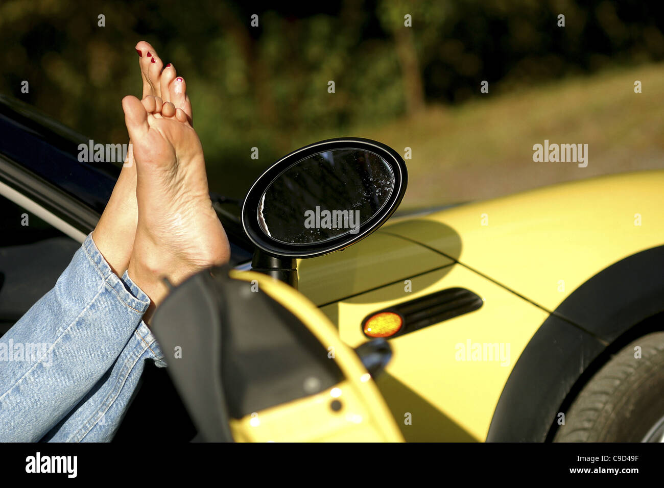 Low section view of a person's feet on a car door Stock Photo - Alamy