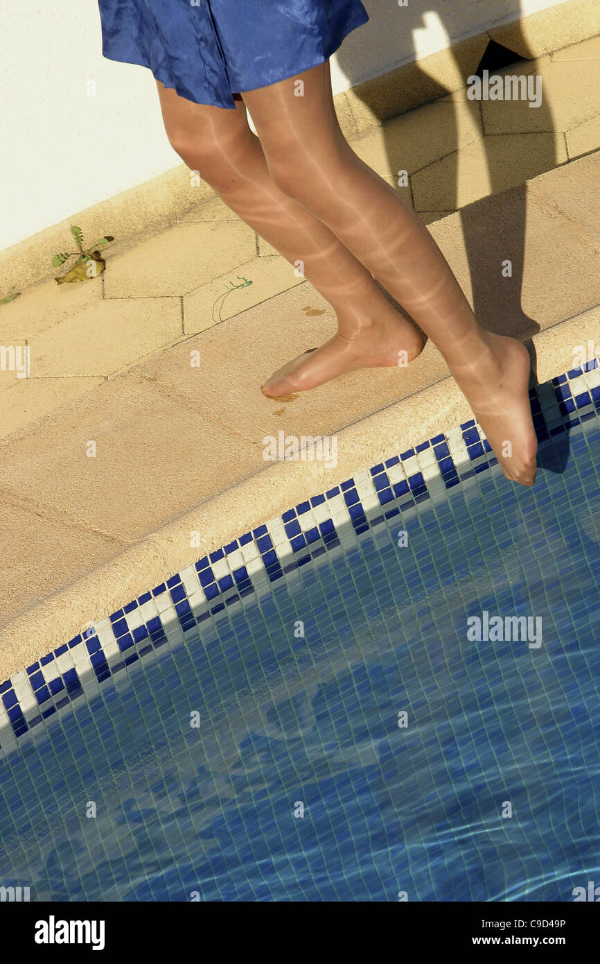 Low section view of a person's legs dipping their toe into a swimming ...