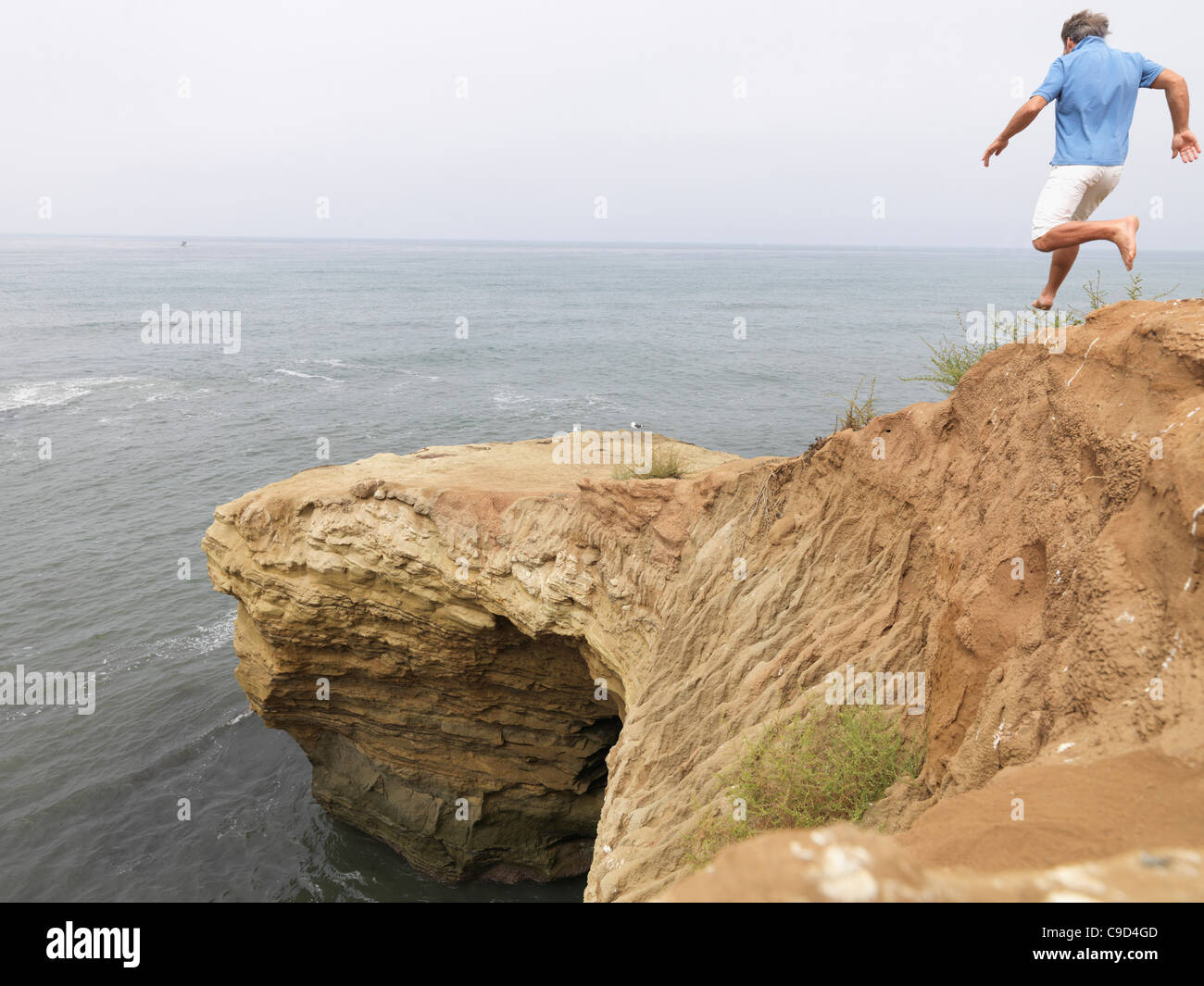 USA, California, San Diego, Man running down sandy slope towards ocean ...