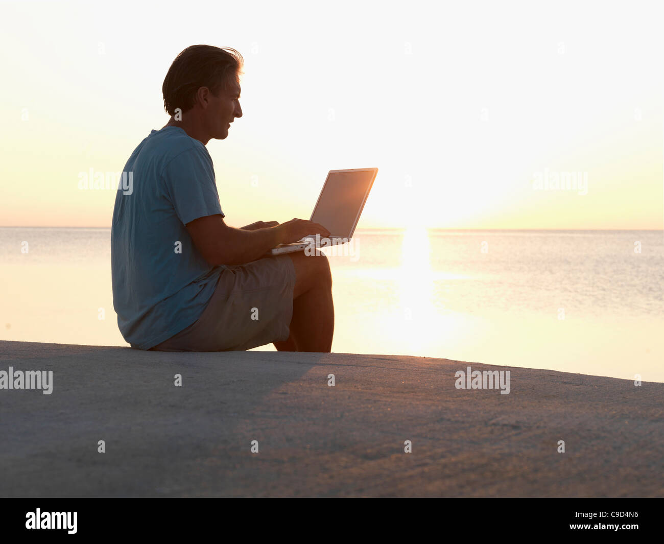 USA, Florida, Keys, Man working on laptop computer from stone walkway ...