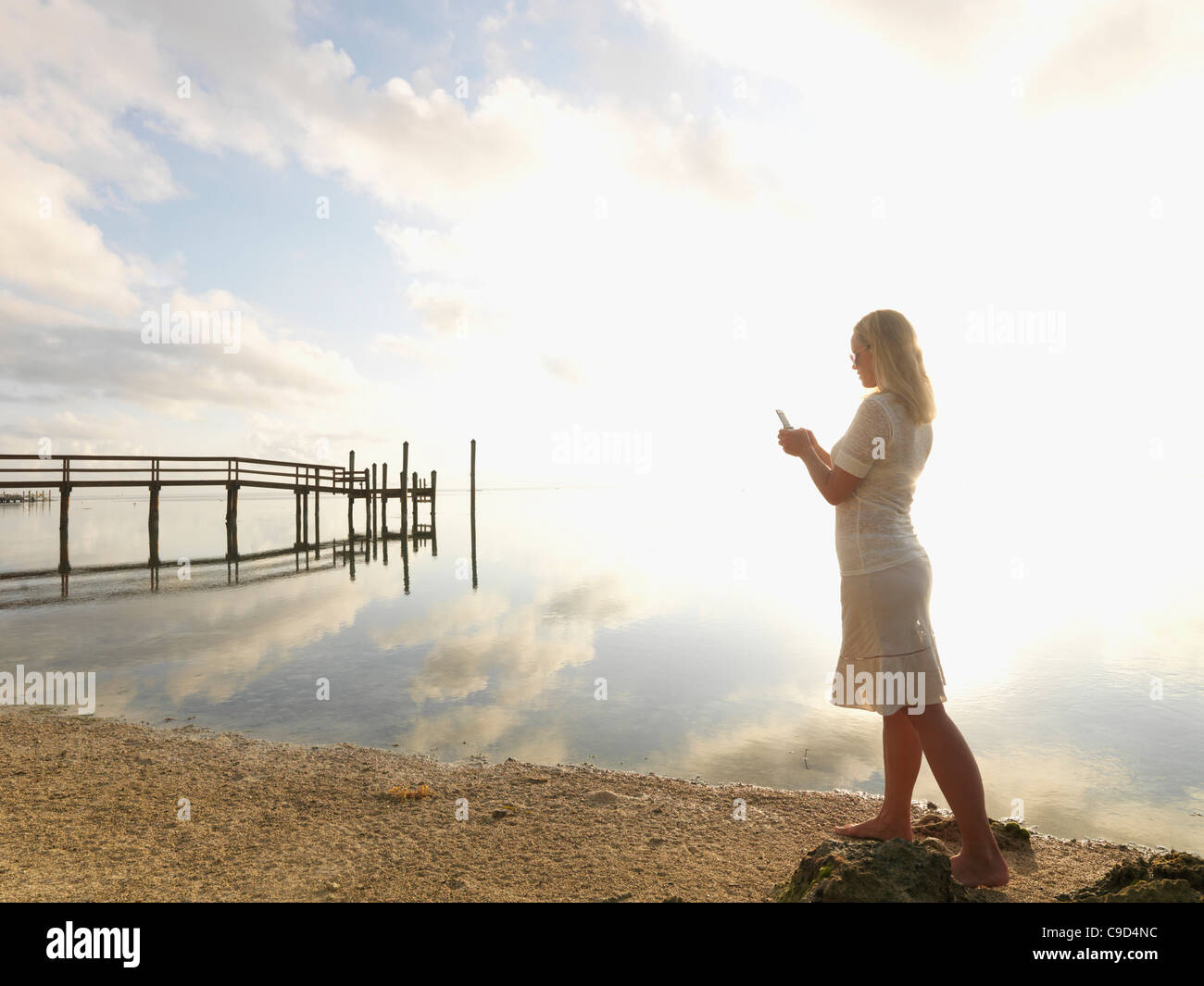 USA, Florida, Keys, Woman sending text message while walking along ...