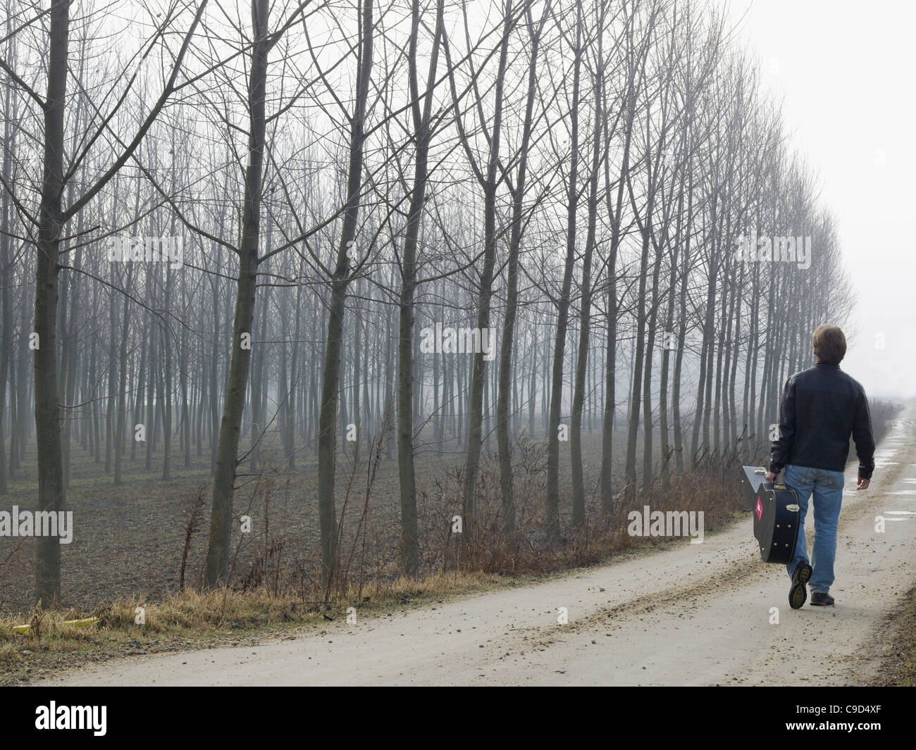 Italy, Piedmont, Man walking up dirt road carrying guitar Stock Photo ...