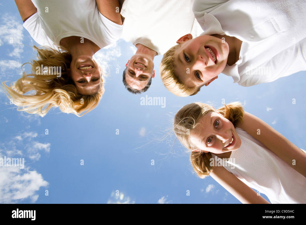 Low-angle view of family against a blue sky looking at camera Stock ...