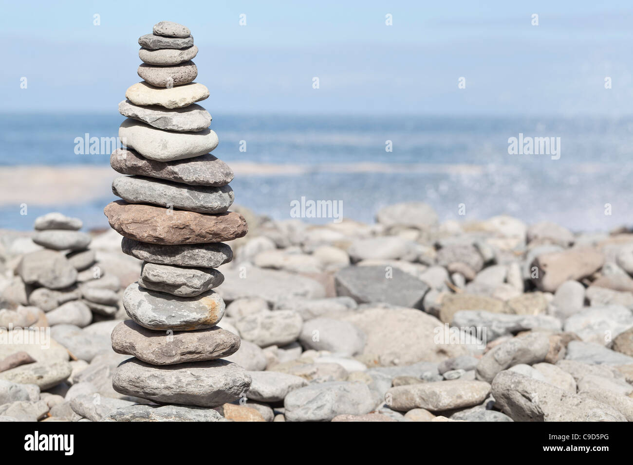 Stacked pebbles at the beach with waves breaking in the background ...