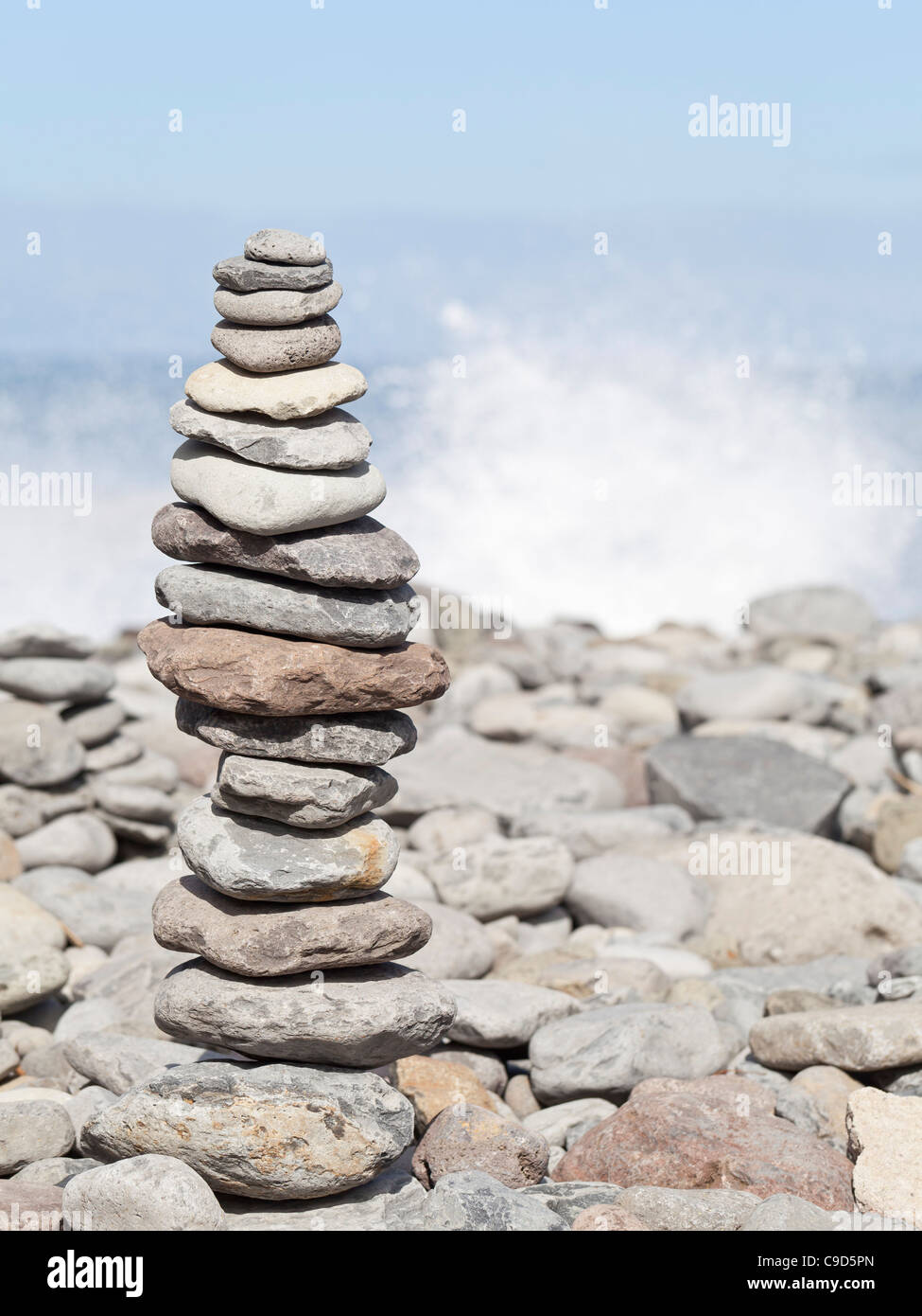 Stacked pebbles at the beach with waves breaking in the background ...