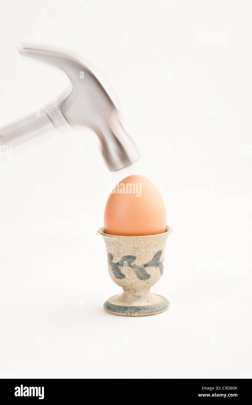 Hammer hitting a brown egg Stock Photo - Alamy