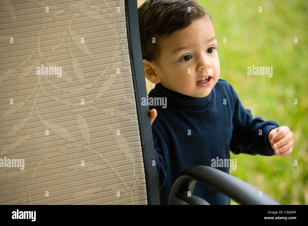 Elevated view of a little boy standing by a chair Stock Photo - Alamy