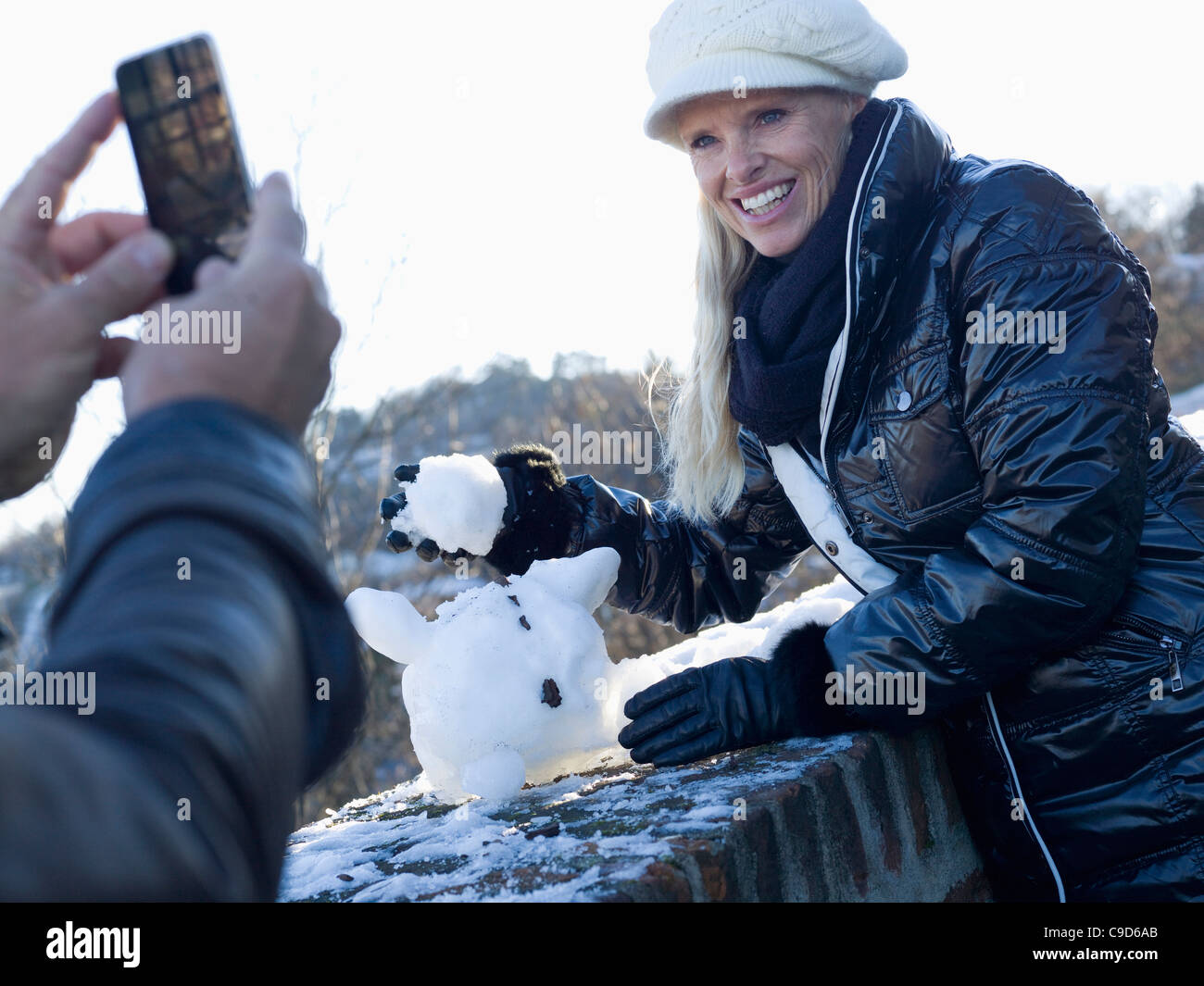 Italy, Piedmont, Couple taking picture of miniature snowman Stock Photo ...