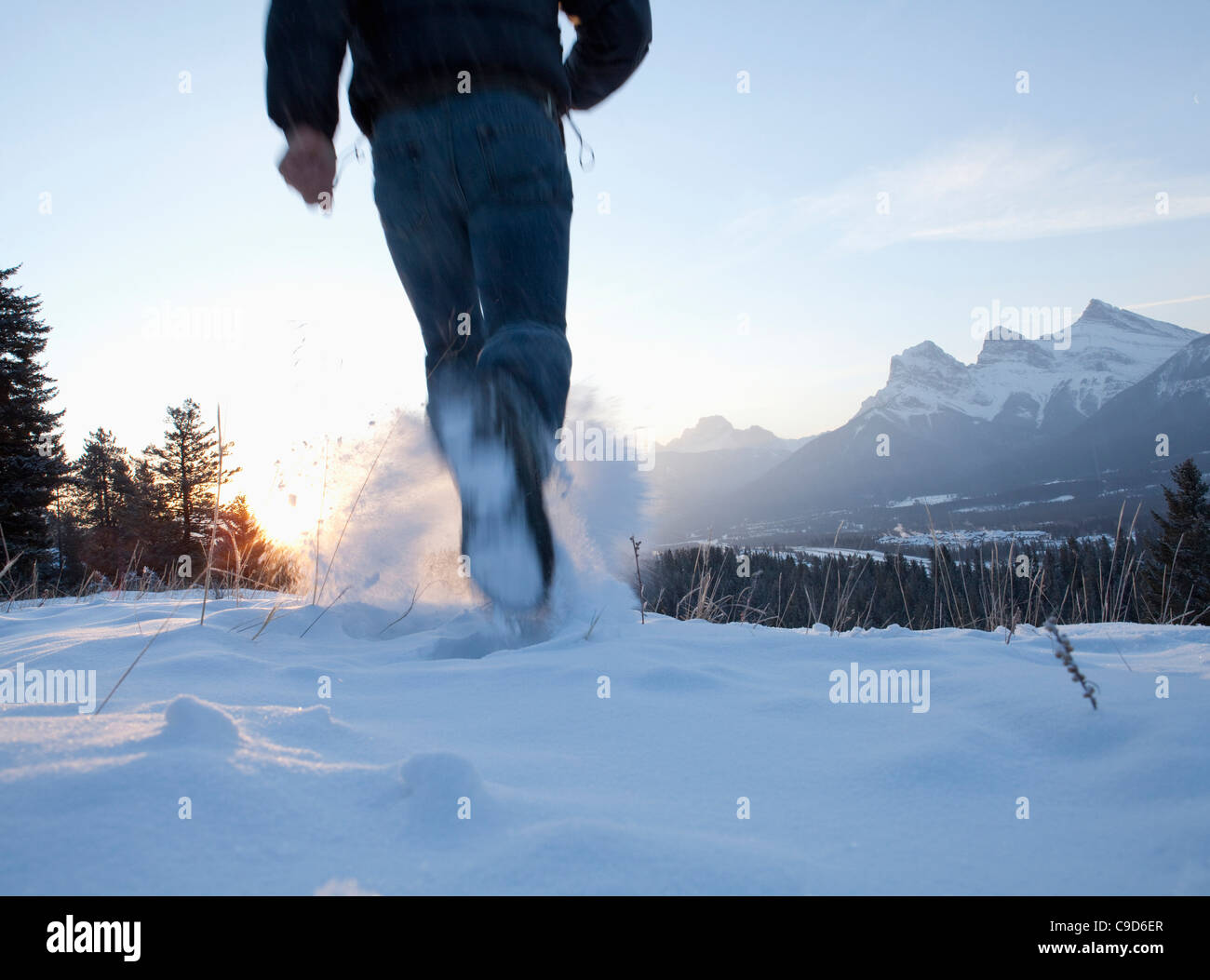 Canada, Alberta, Banff National Park, Man running through snow on cold ...
