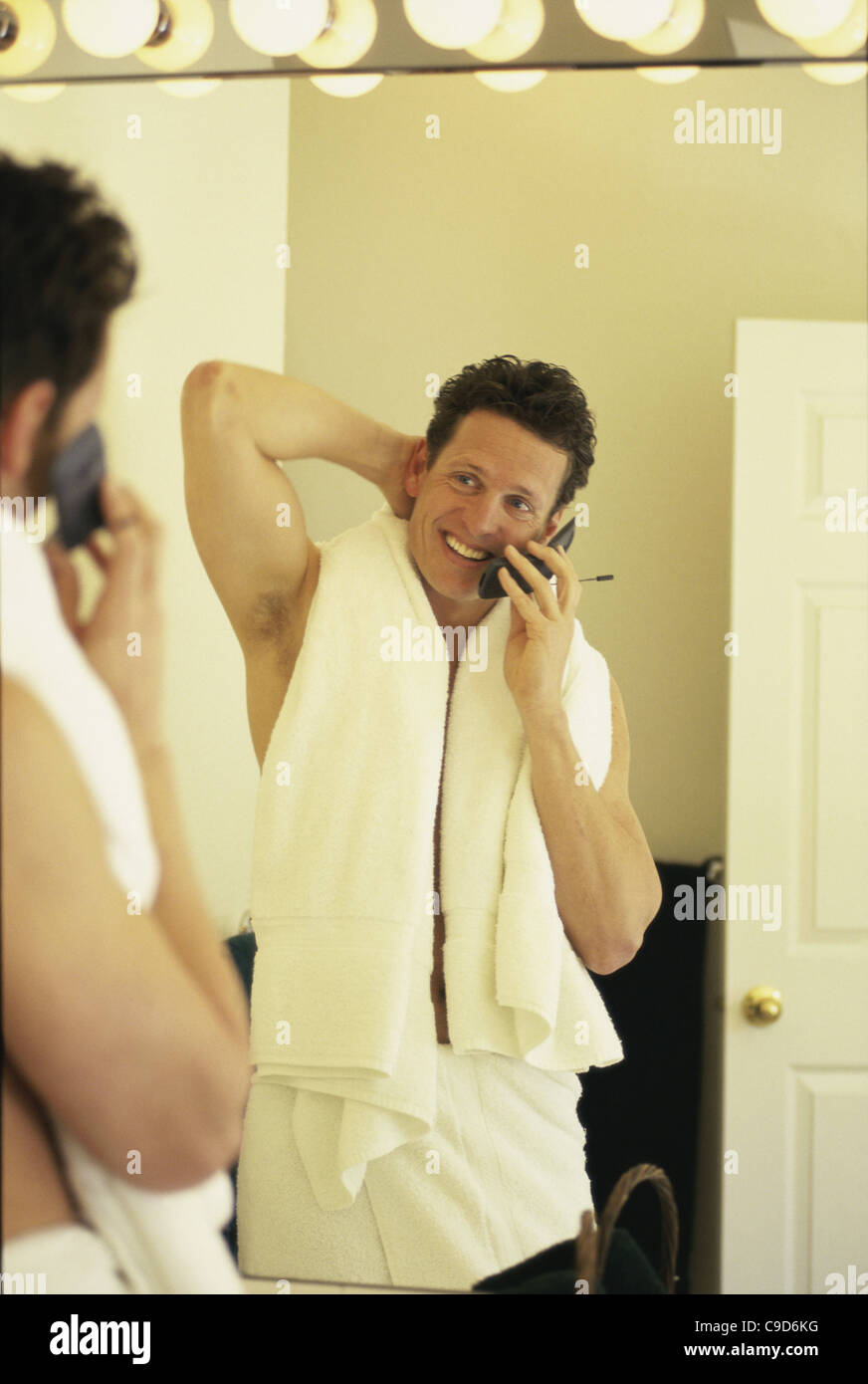 Young man talking on a mobile phone looking into a mirror Stock Photo ...