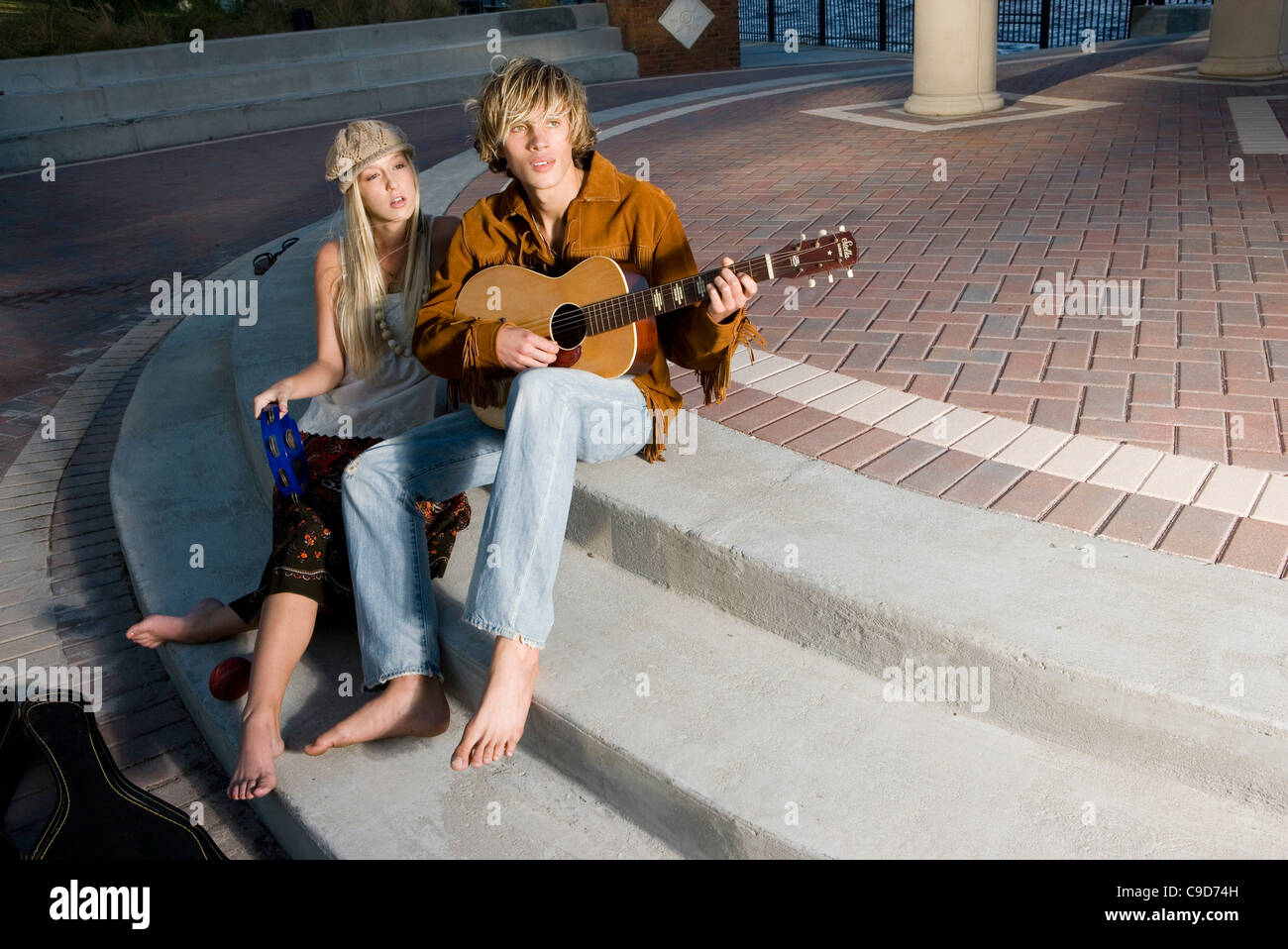 A young Hippie couple in a park playing guitar and tambourine Stock ...