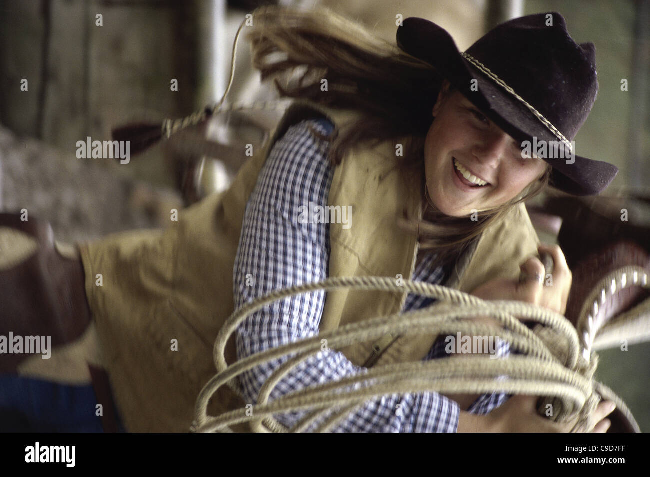 Portrait of a cowgirl holding a rope smiling Stock Photo - Alamy