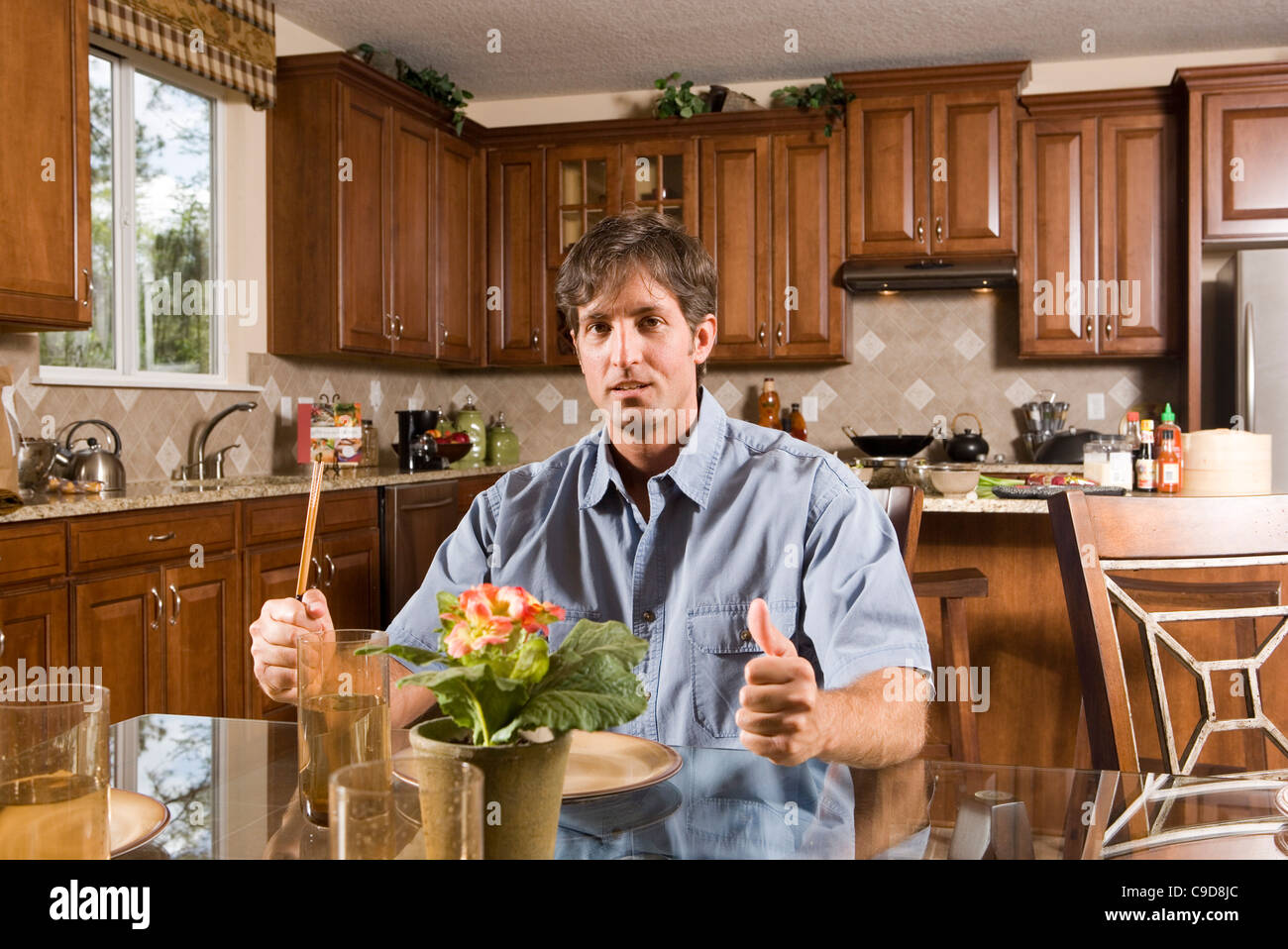 Portrait of a mid adult man sitting at dining table waiting to be ...