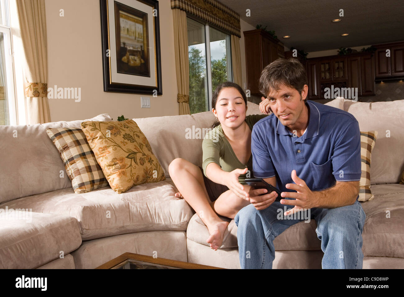 Father and daughter watching TV and fighting over the remote control ...