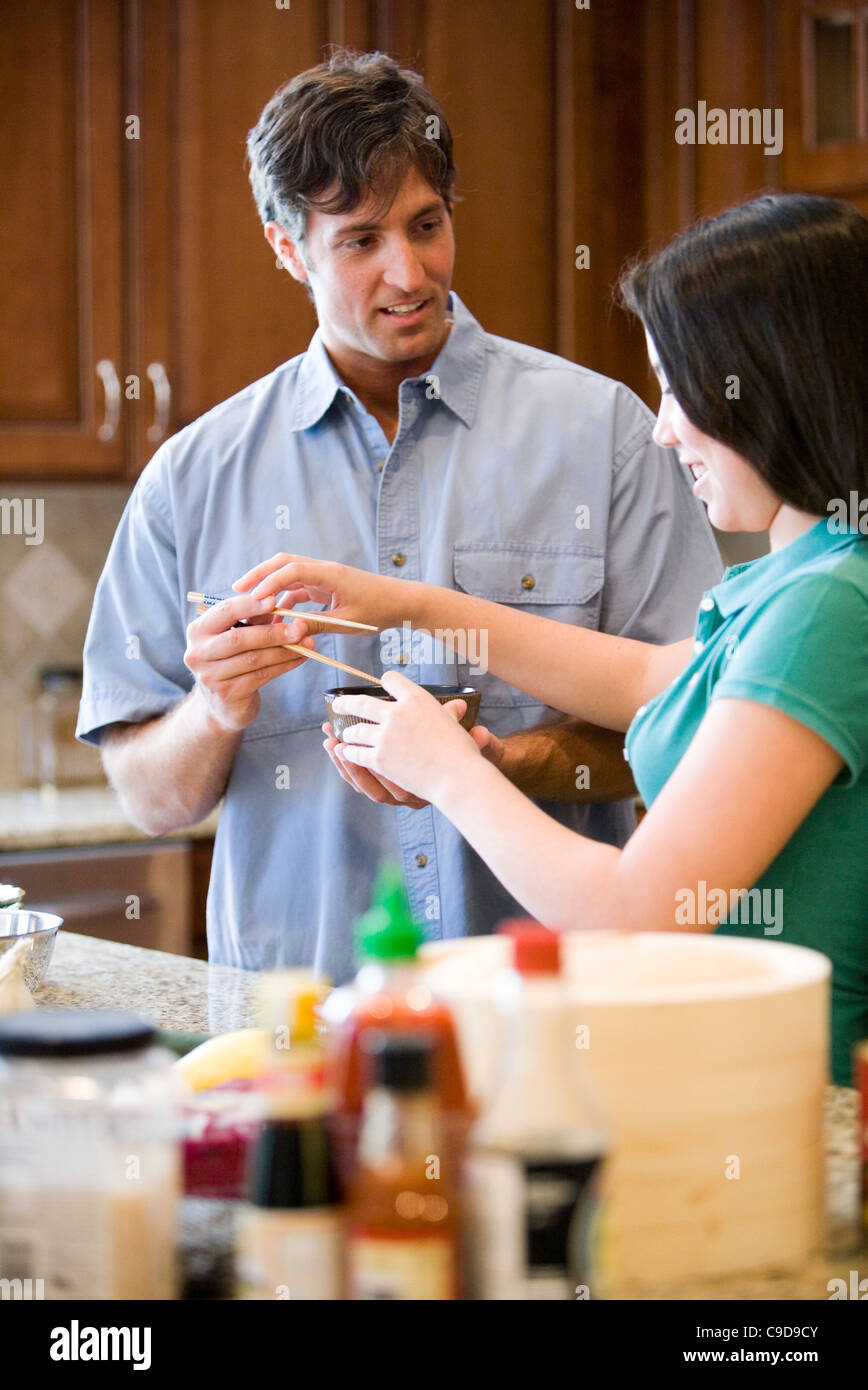 Asian girl showing Caucasian man how to use chopsticks Stock Photo - Alamy