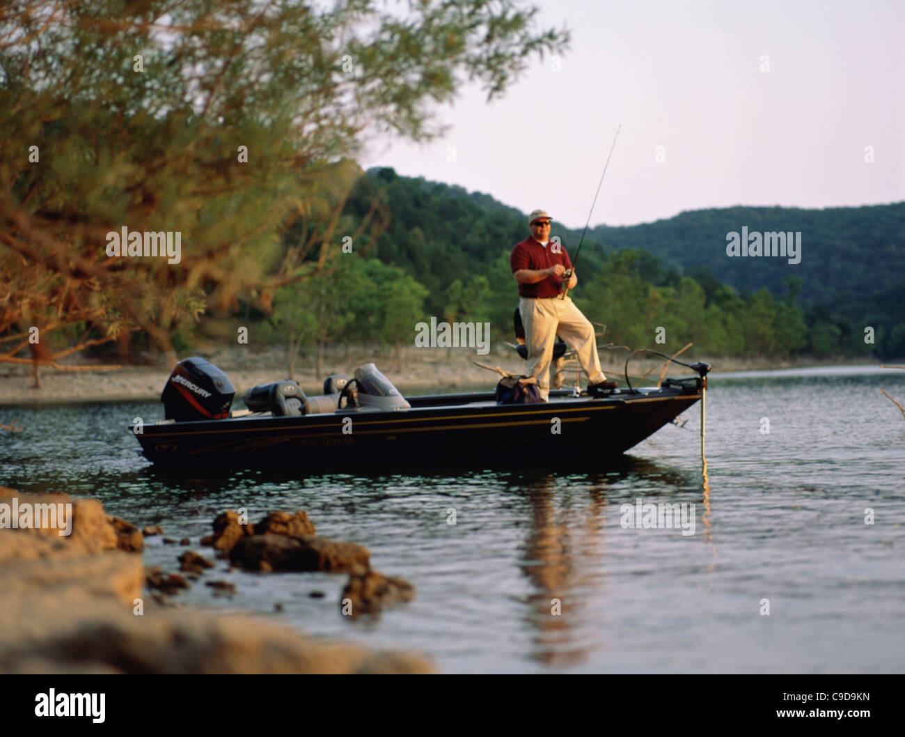 Man standing in a boat fishing Stock Photo - Alamy