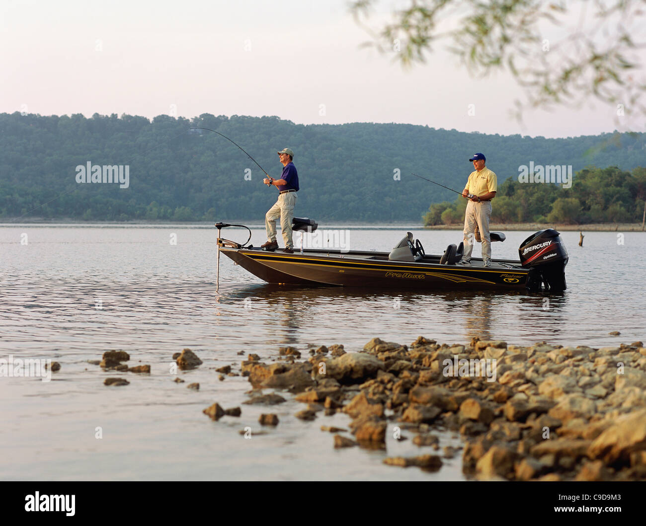 Two people standing in a boat fishing Stock Photo - Alamy