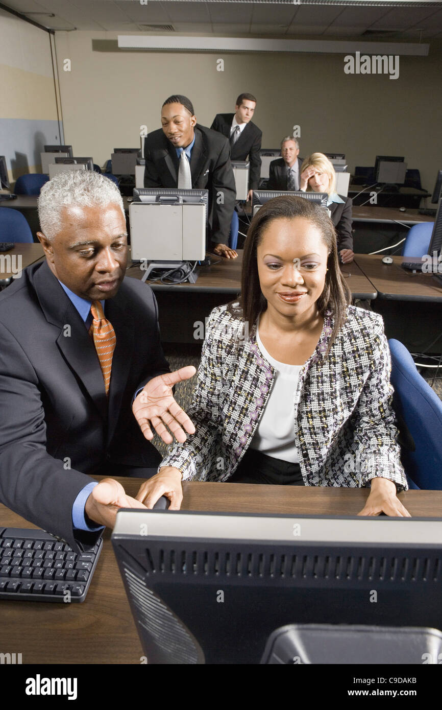 Older man helping younger business colleague in computer lab Stock ...