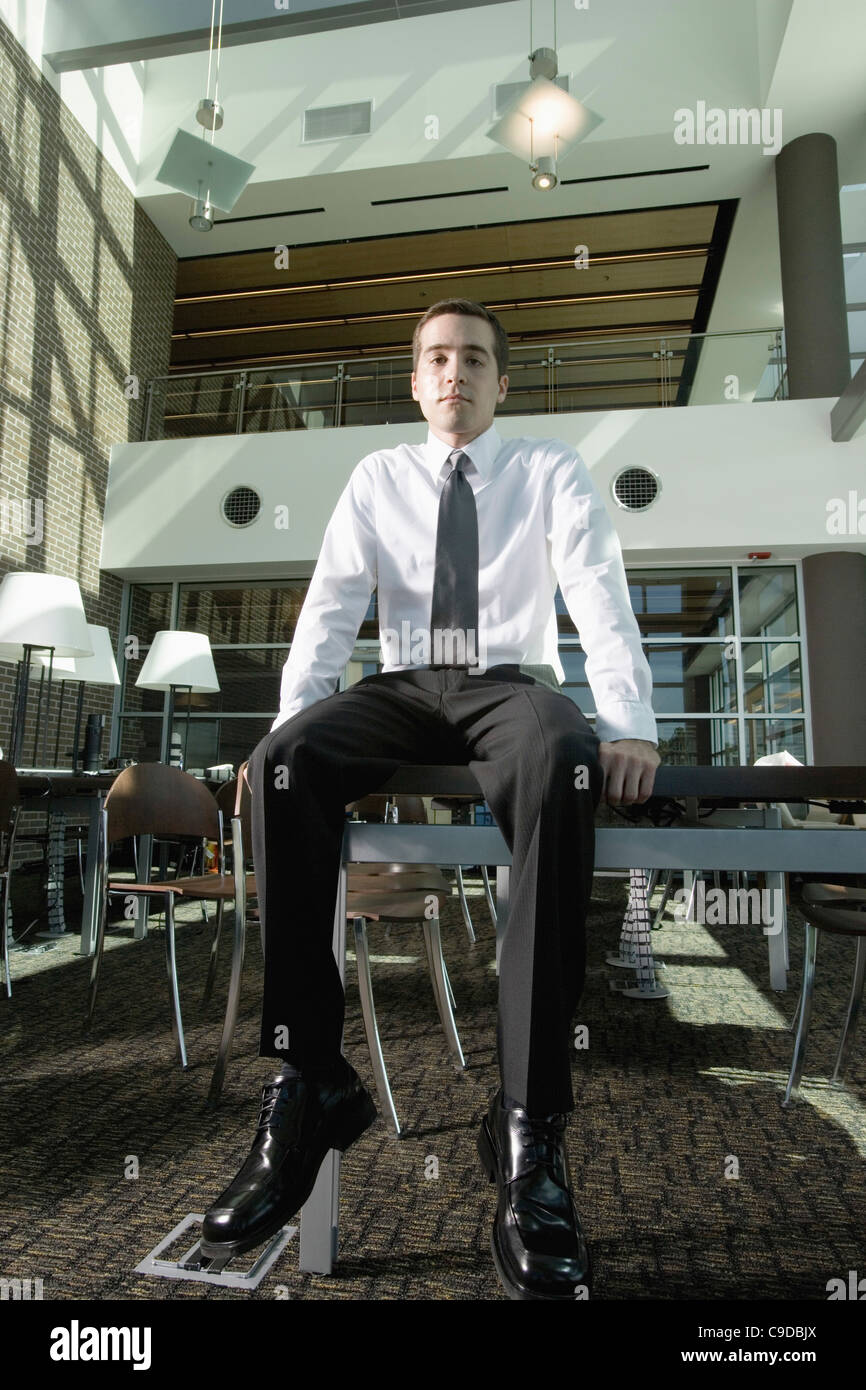 Office worker sitting on table Stock Photo - Alamy