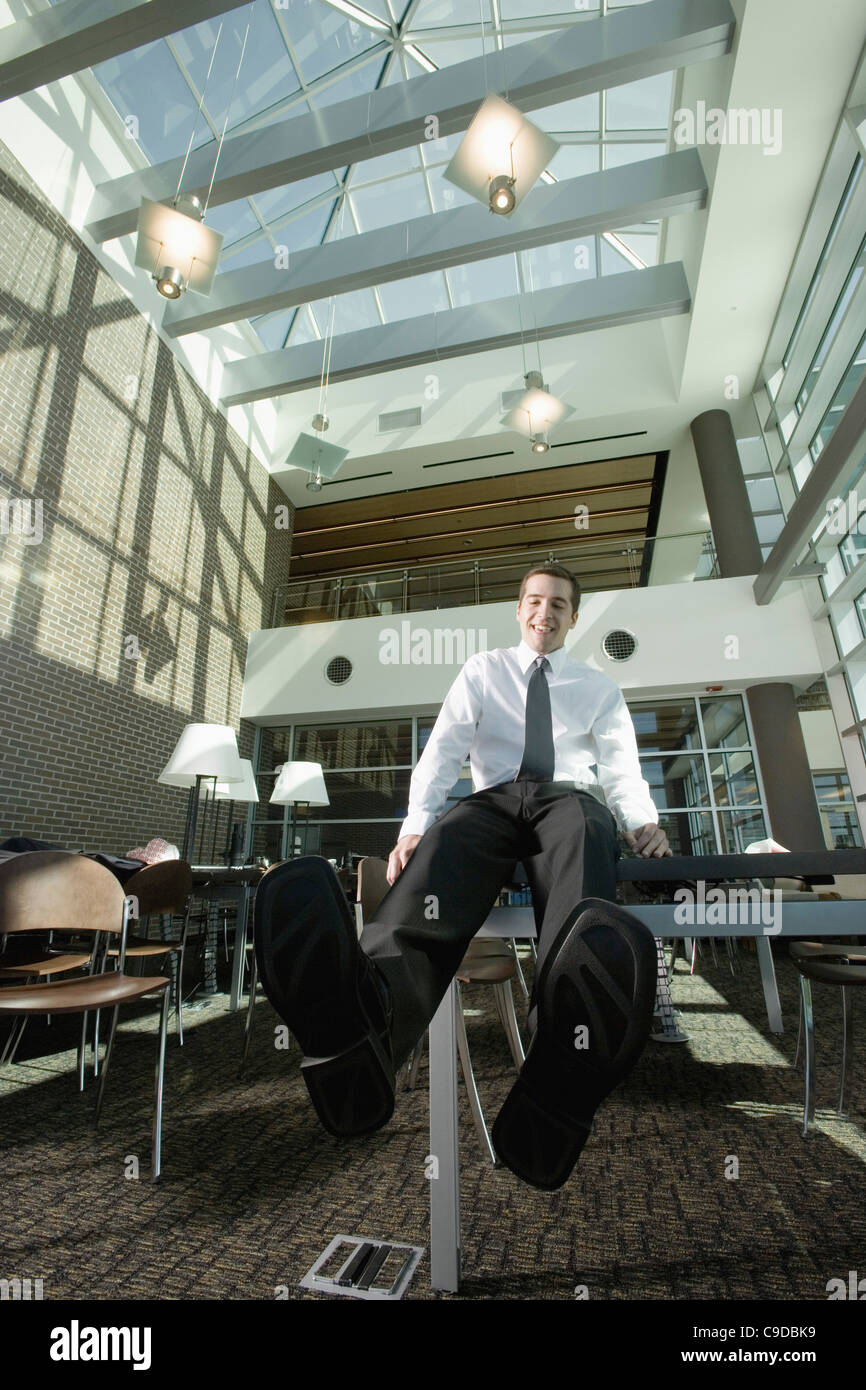Office worker sitting on table Stock Photo - Alamy