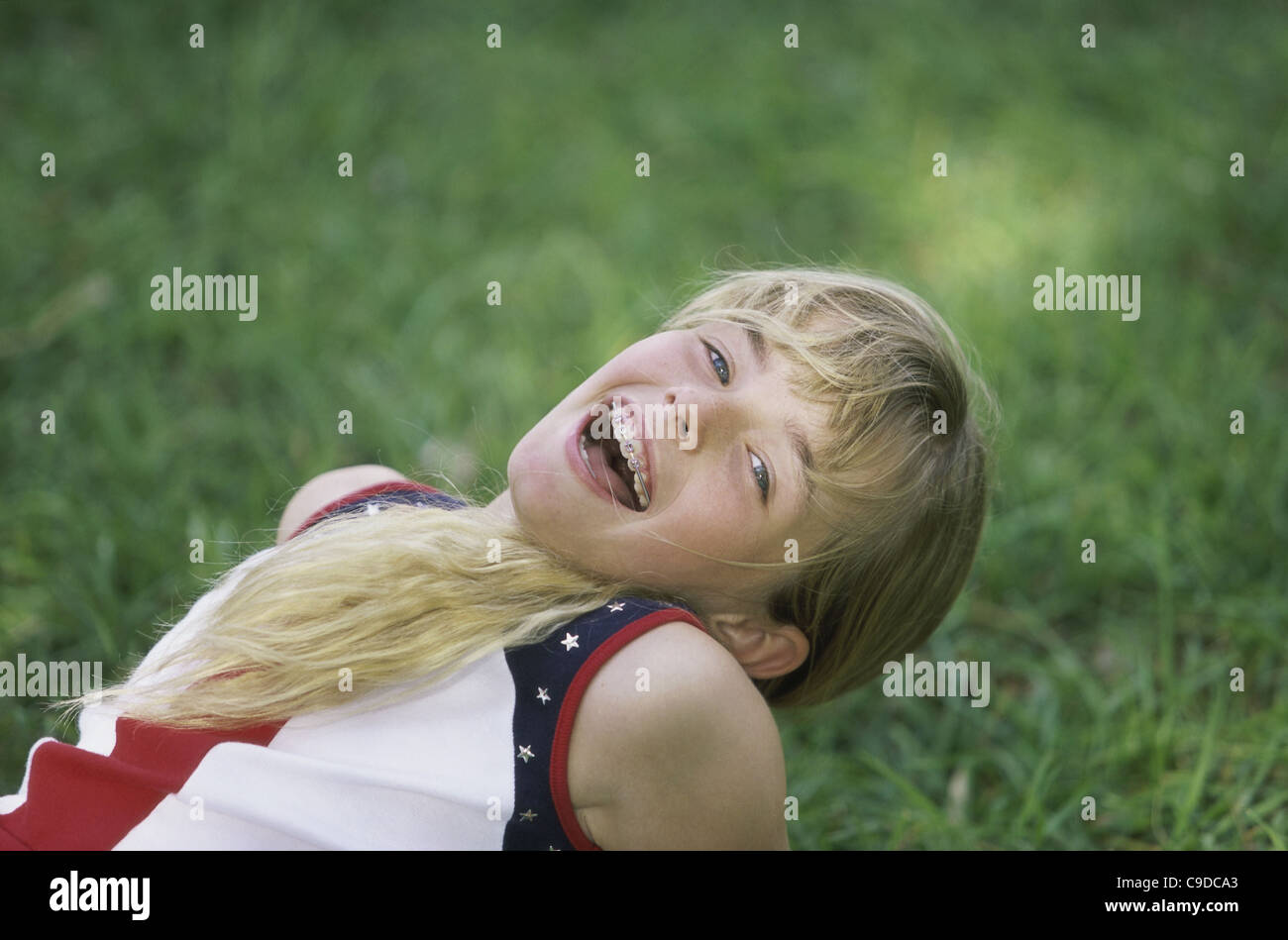 Portrait of a girl lying on a lawn smiling Stock Photo - Alamy
