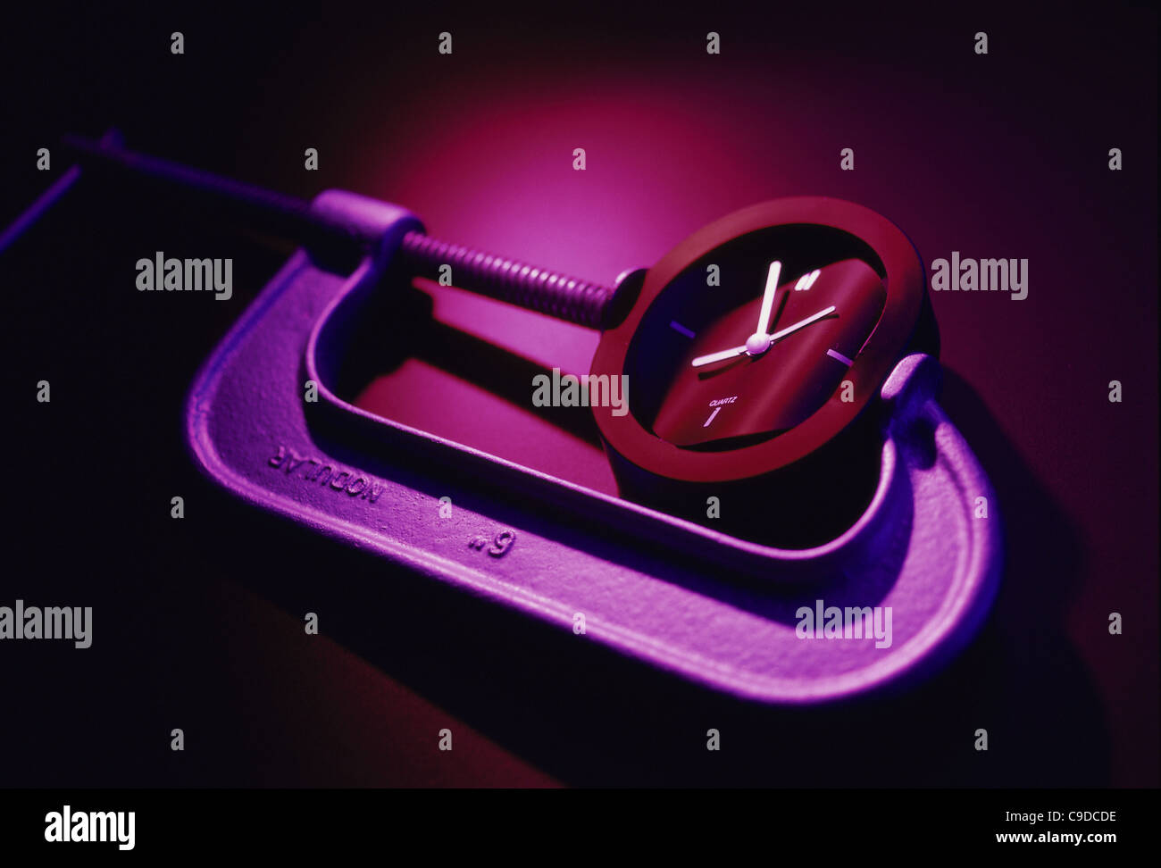 Clock being squeezed in a clamp Stock Photo - Alamy