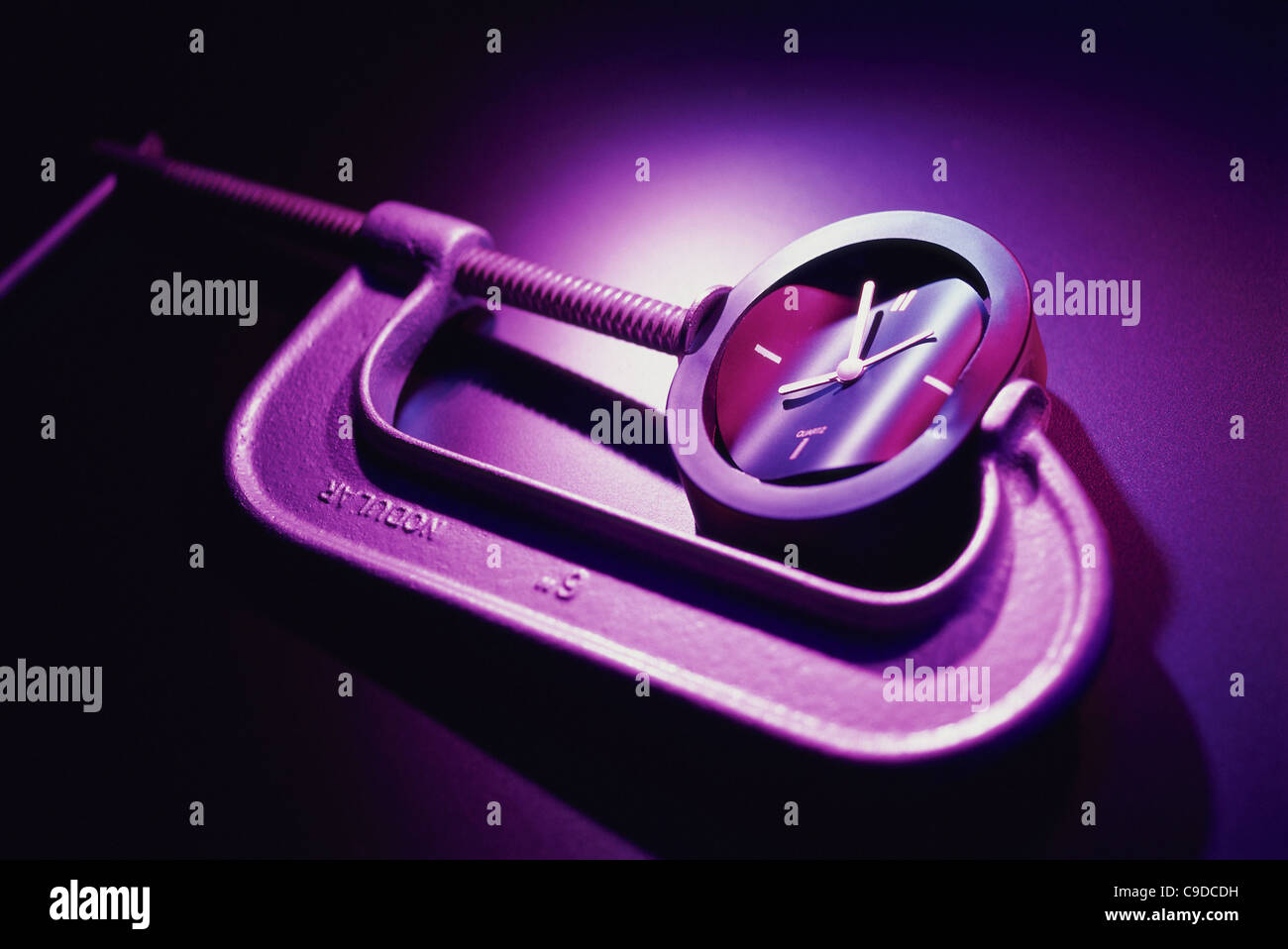 Clock being squeezed in a clamp Stock Photo - Alamy