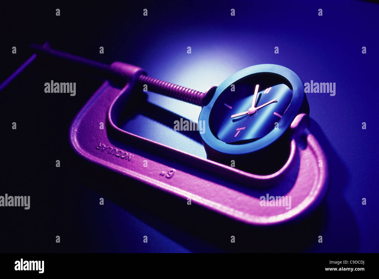 Clock being squeezed in a clamp Stock Photo - Alamy