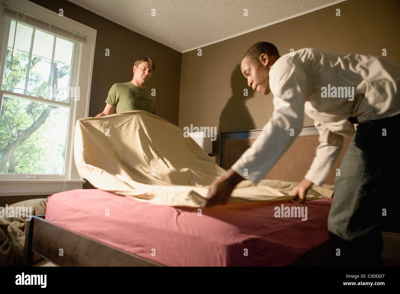 Two young men making a bed Stock Photo - Alamy