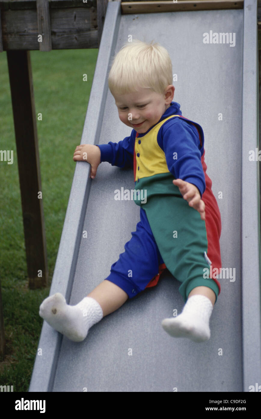 Baby boy coming down a slide in a park Stock Photo - Alamy