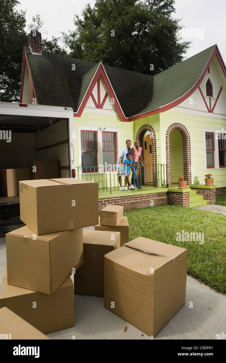 Family standing outside house, with moving boxes piled in driveway ...