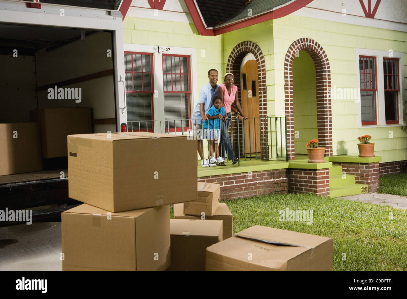 Family standing outside house, with moving boxes piled in driveway ...