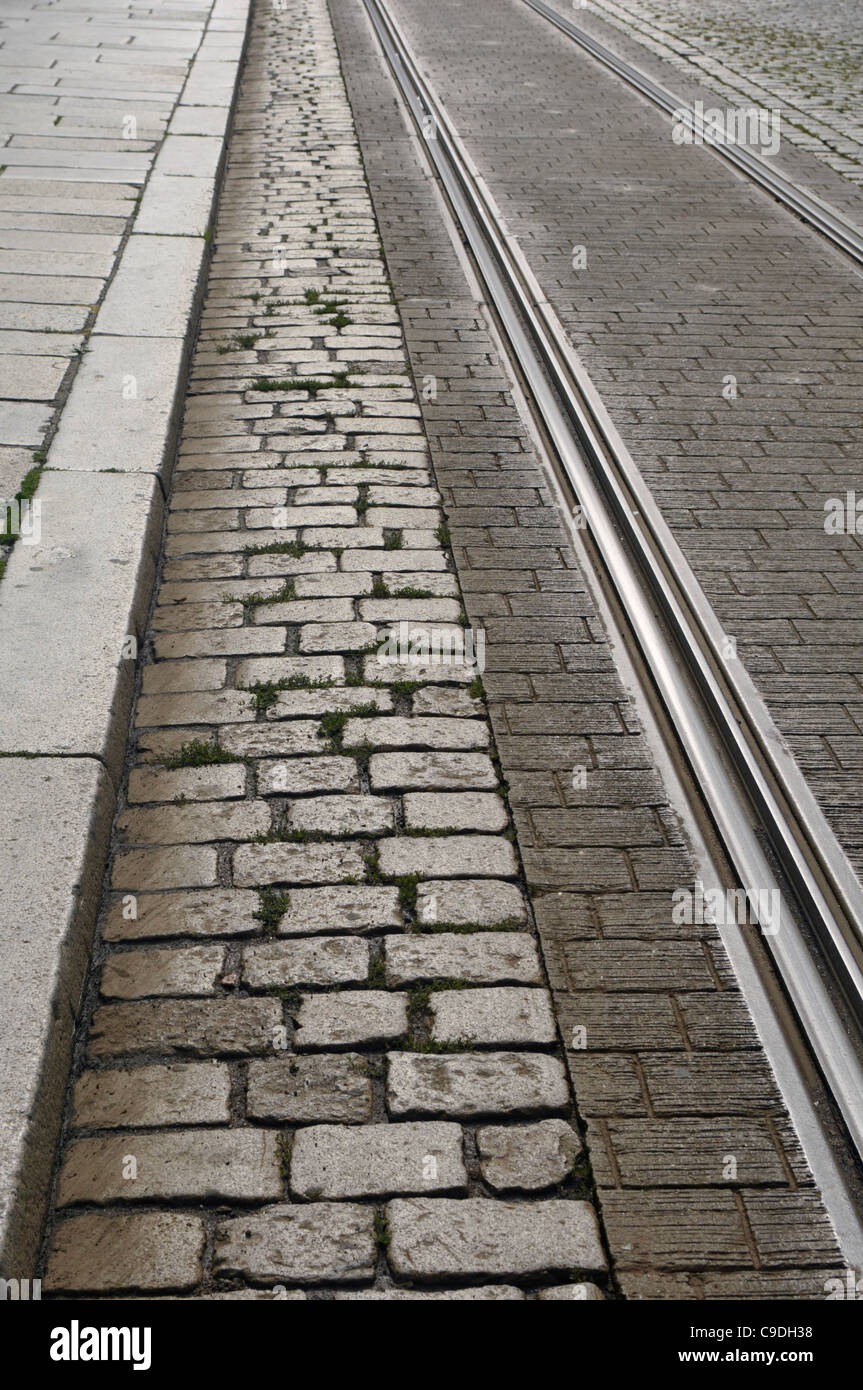 Tram tracks embedded in down the middle of an old cobblestone road ...