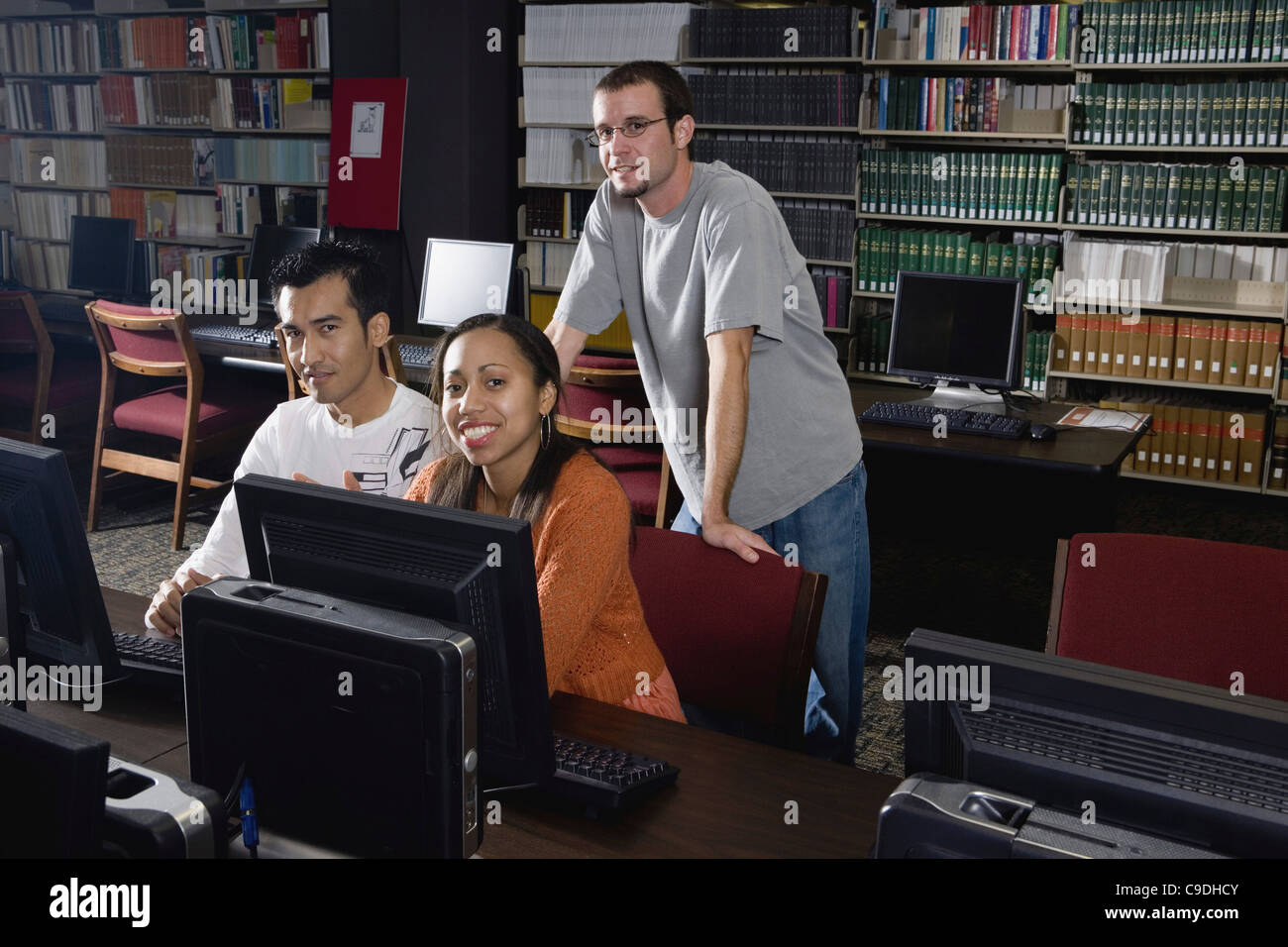 Three university students using computers in the library Stock Photo ...
