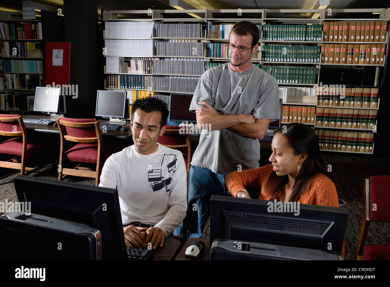Three university students using computers in the library Stock Photo ...