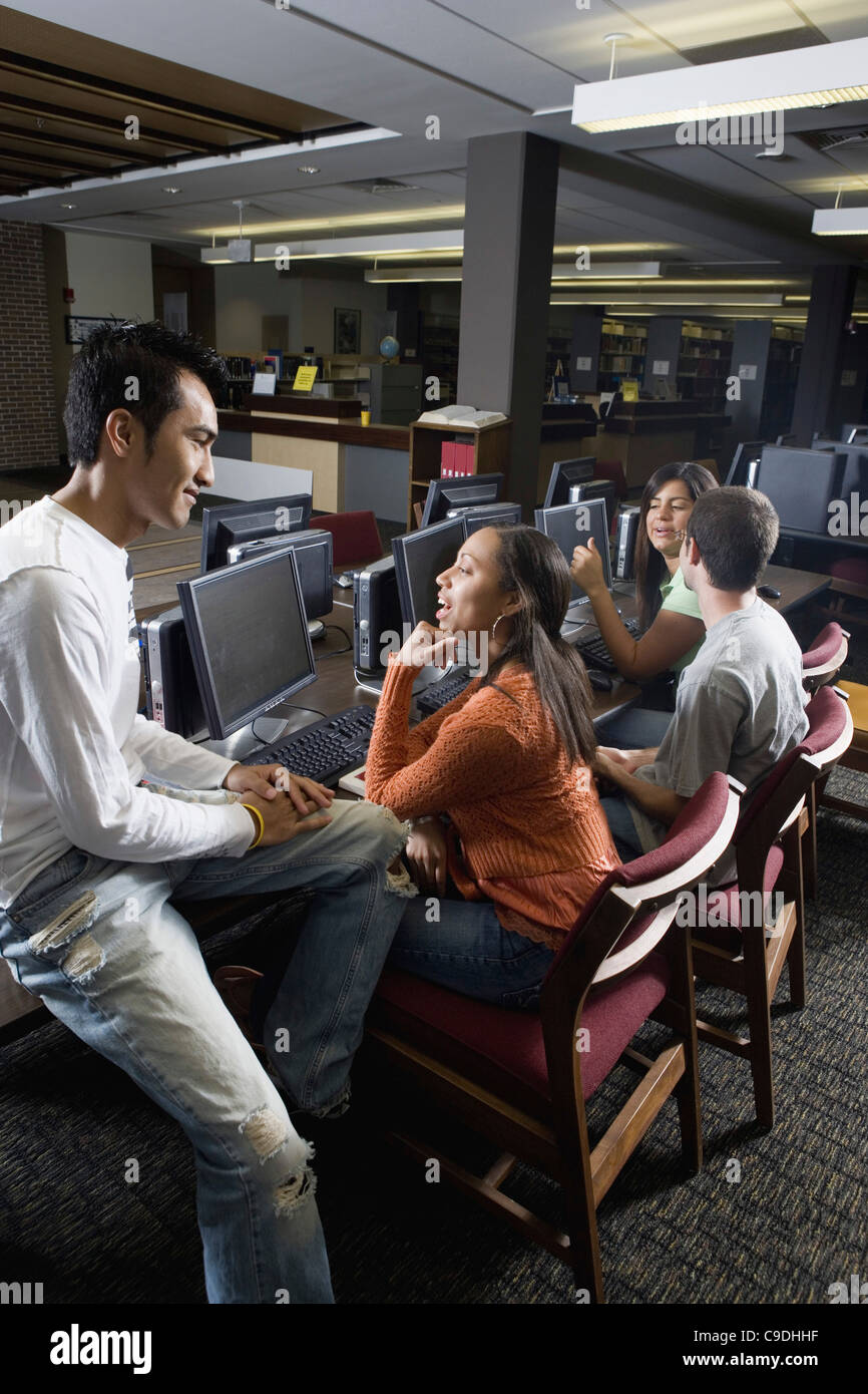 Students conversing while using computers in the library Stock Photo ...