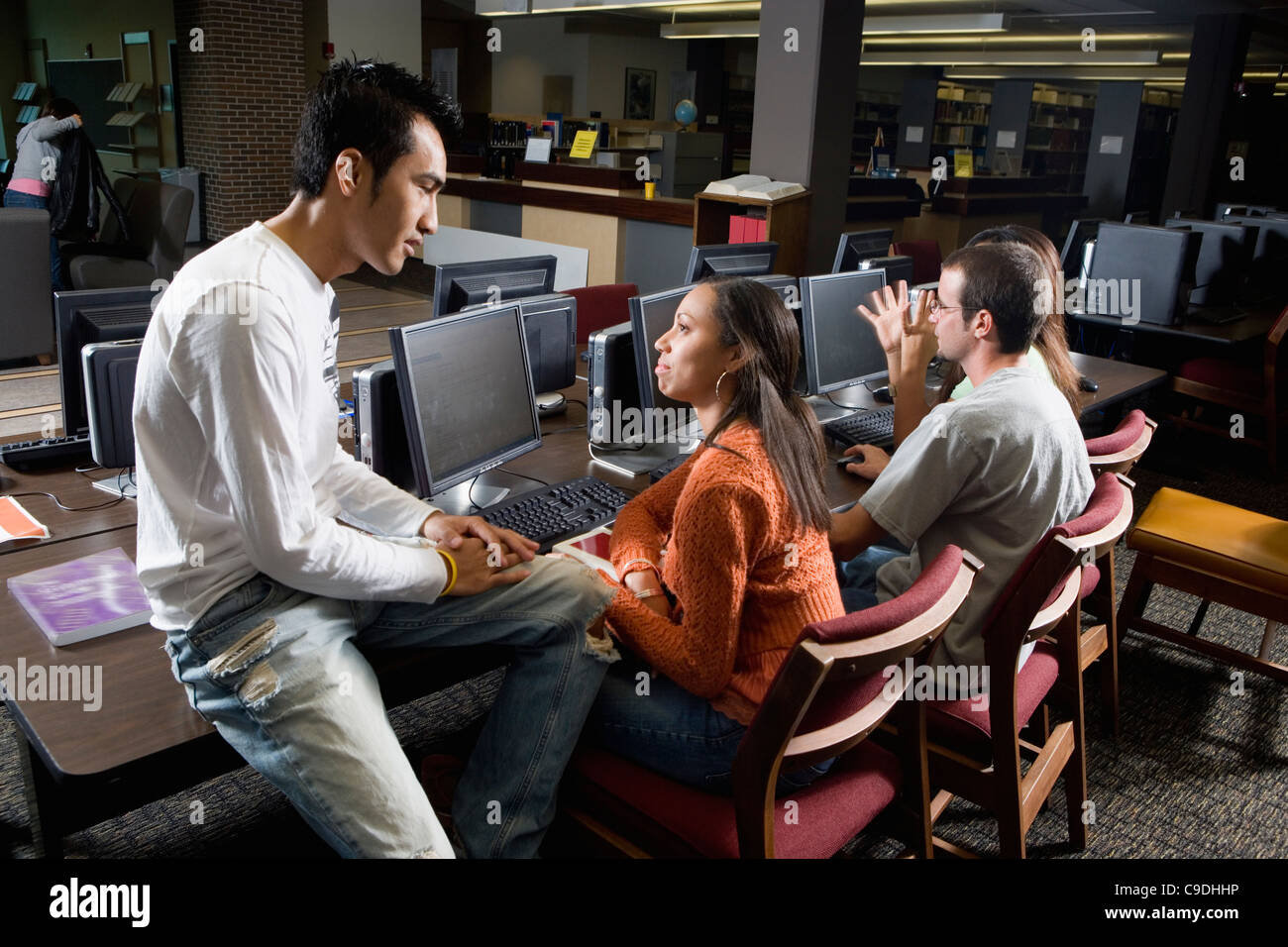 Students conversing while using computers in the library Stock Photo ...