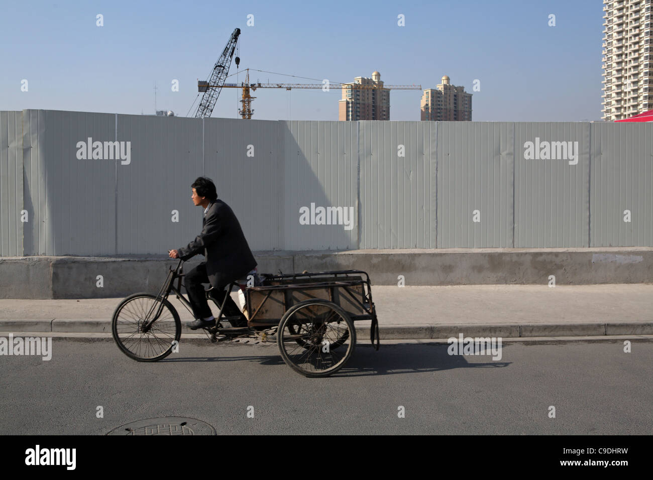 migrant worker on tricycle passes building development in central ...