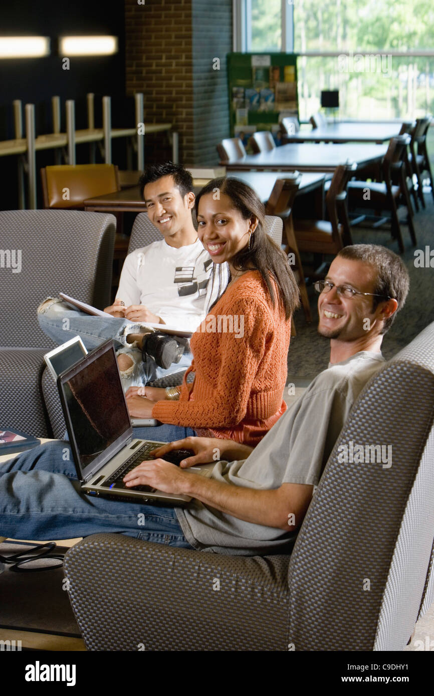Students with laptop computers in library sitting on sofas studying ...