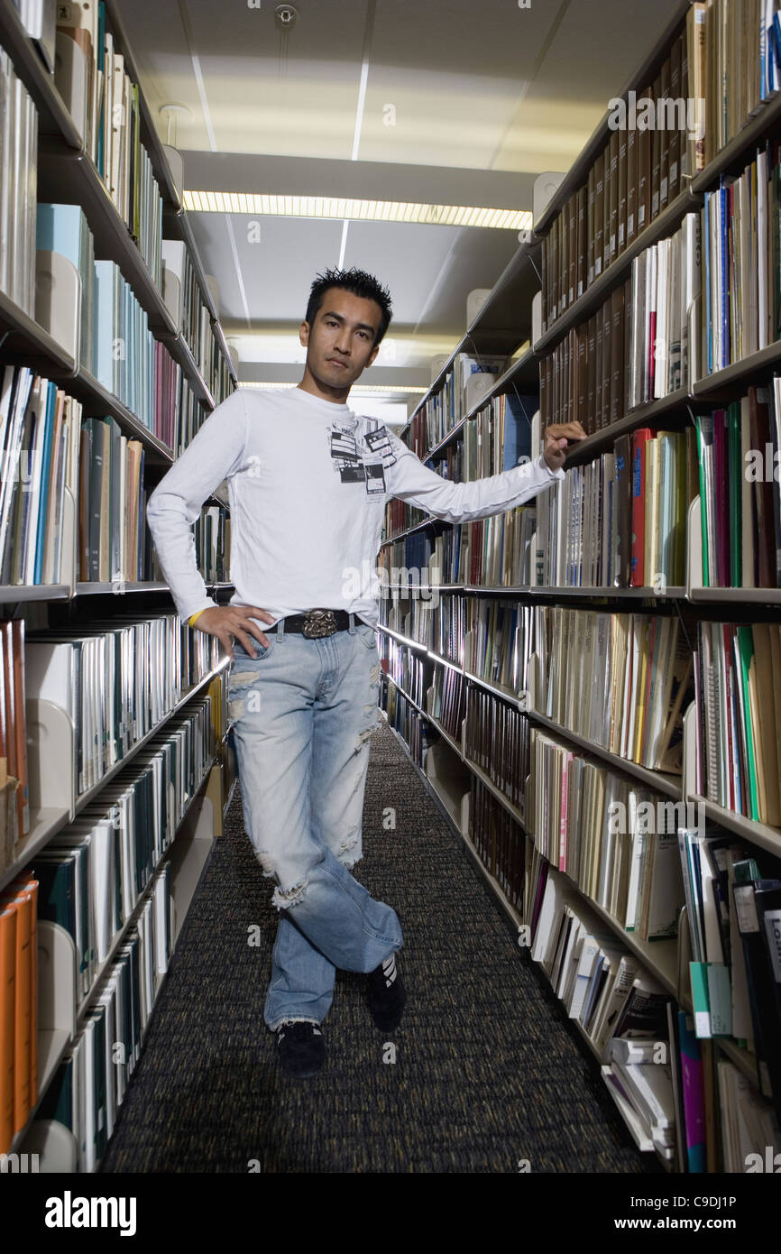 Portrait of a student standing in the library amidst book stacks Stock ...