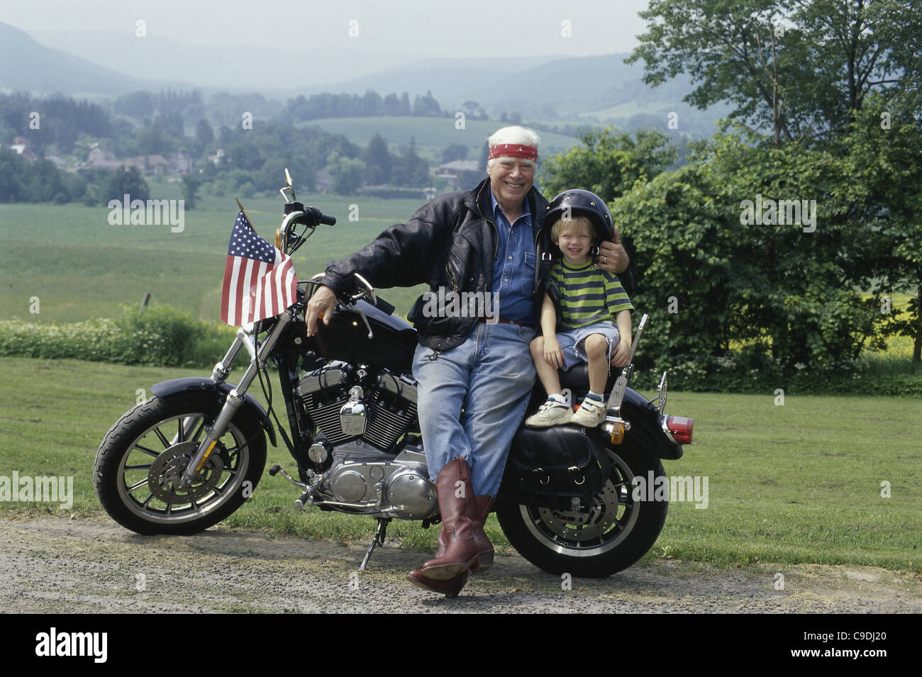 Portrait of a grandfather sitting on a motorcycle with his grandson ...