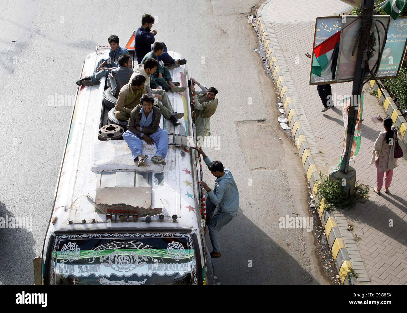 Commuters travel on the roof of an overloaded passenger bus as ...