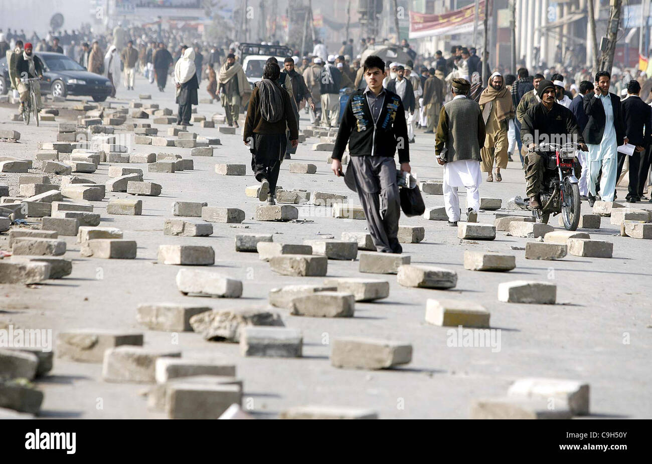 People pass through bricks which were pelted by angry protesters on ...