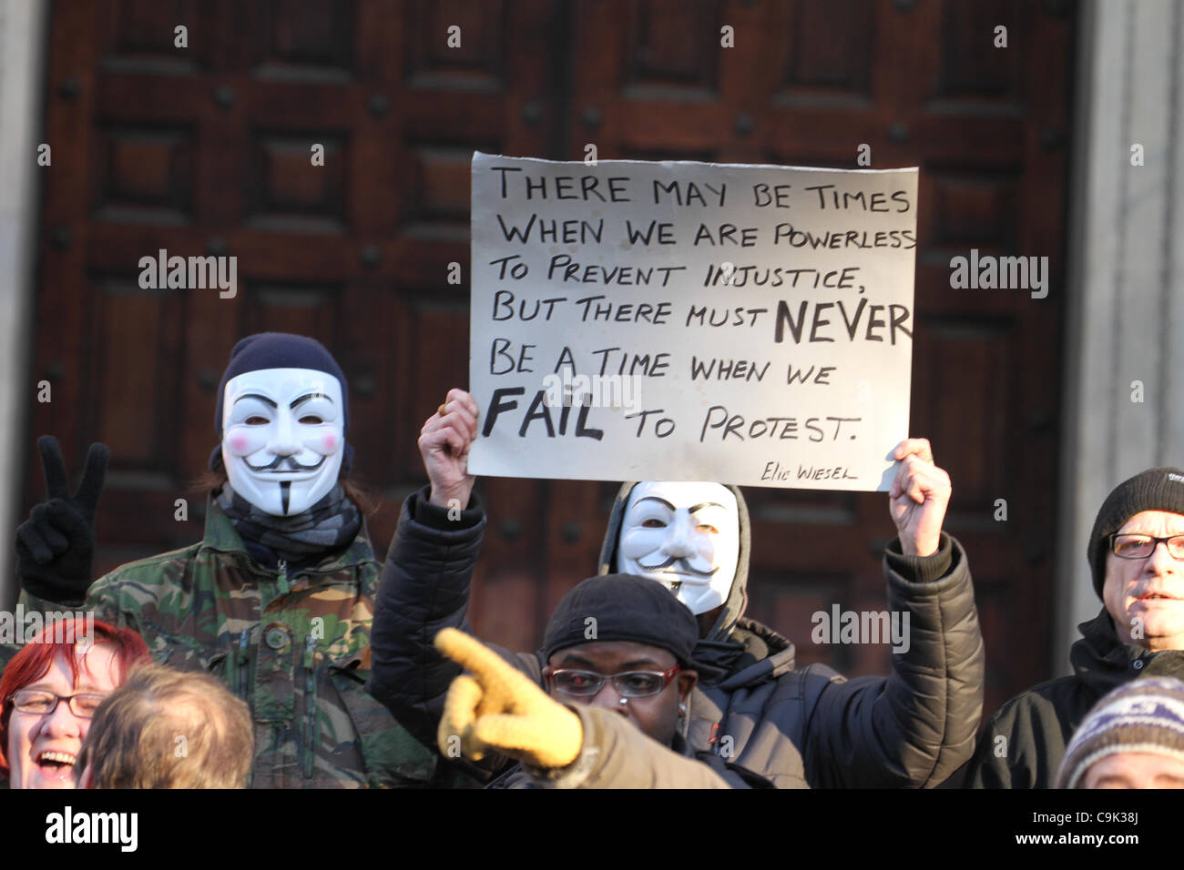 Two anonymous protesters hold a placard at the steps of St Paul's ...