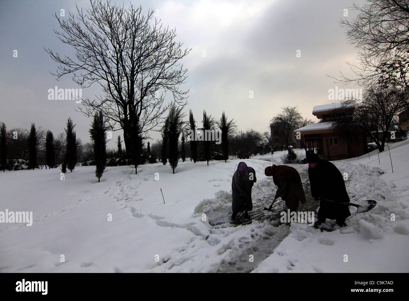 An kashmiri muslims removes snow in a snow covered park during sunny ...