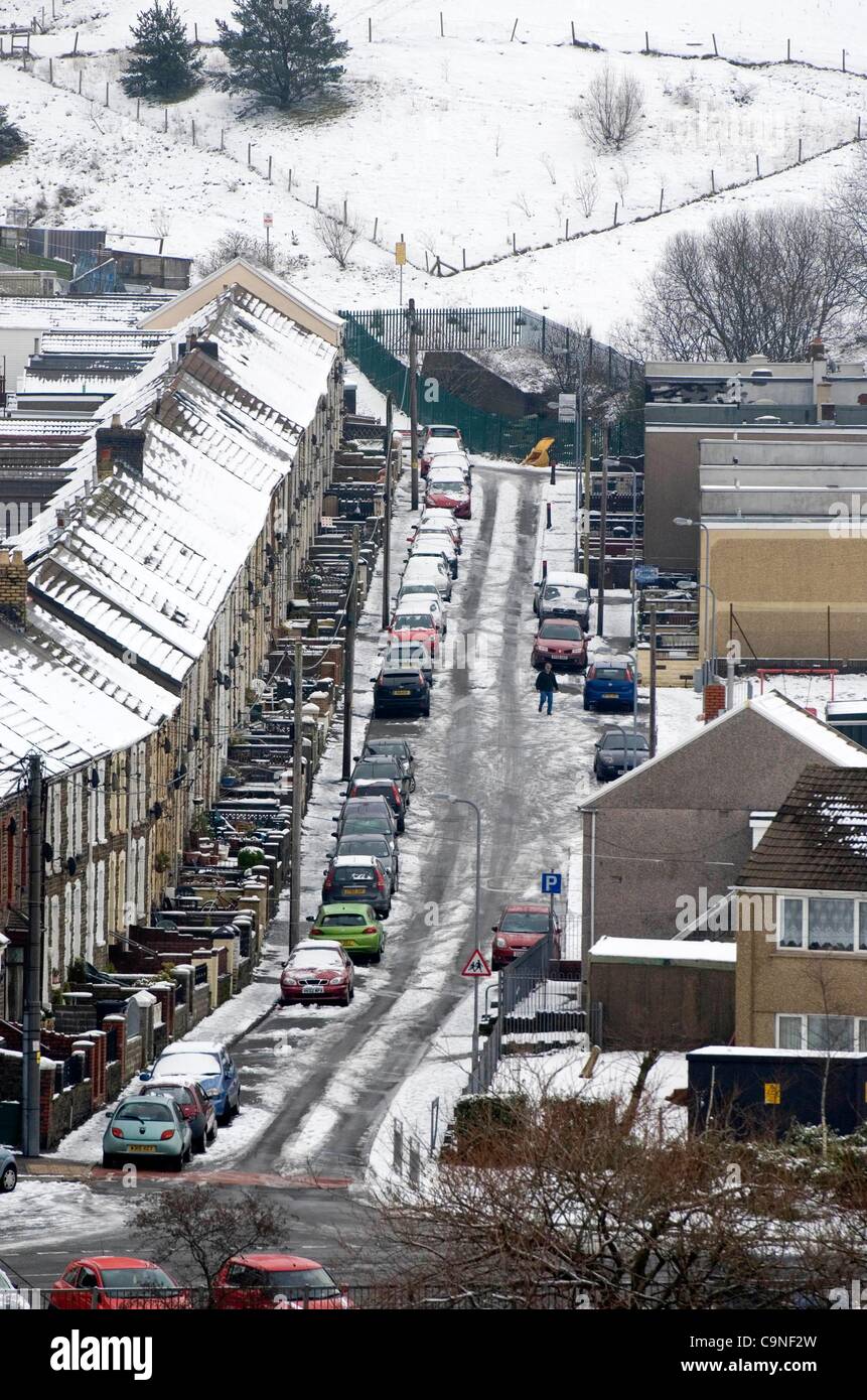 A man making his way down a snow covered street in the small village of ...