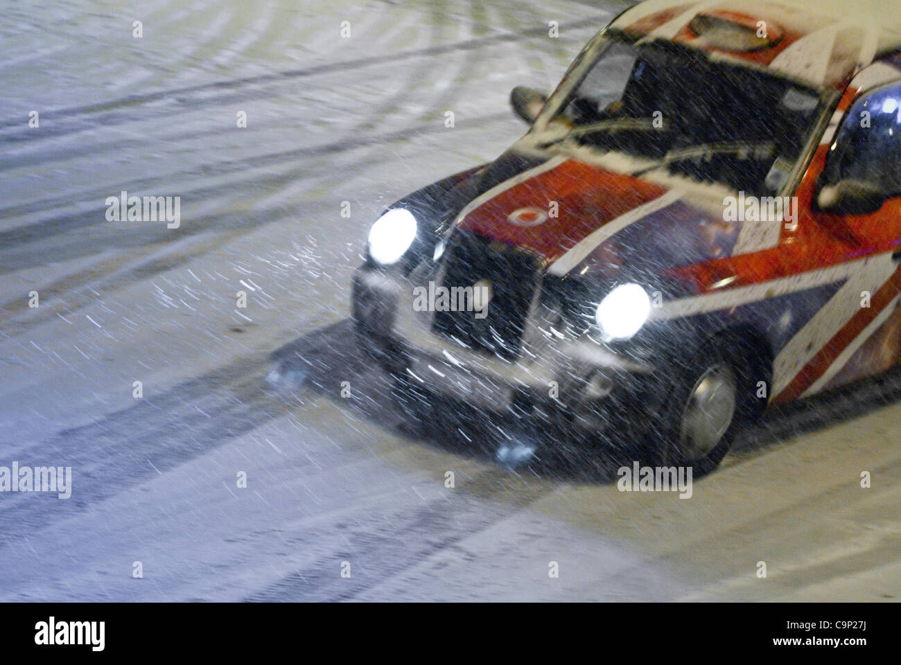 Black cab with Union Jack Vodaphone branding, driving at night in the ...