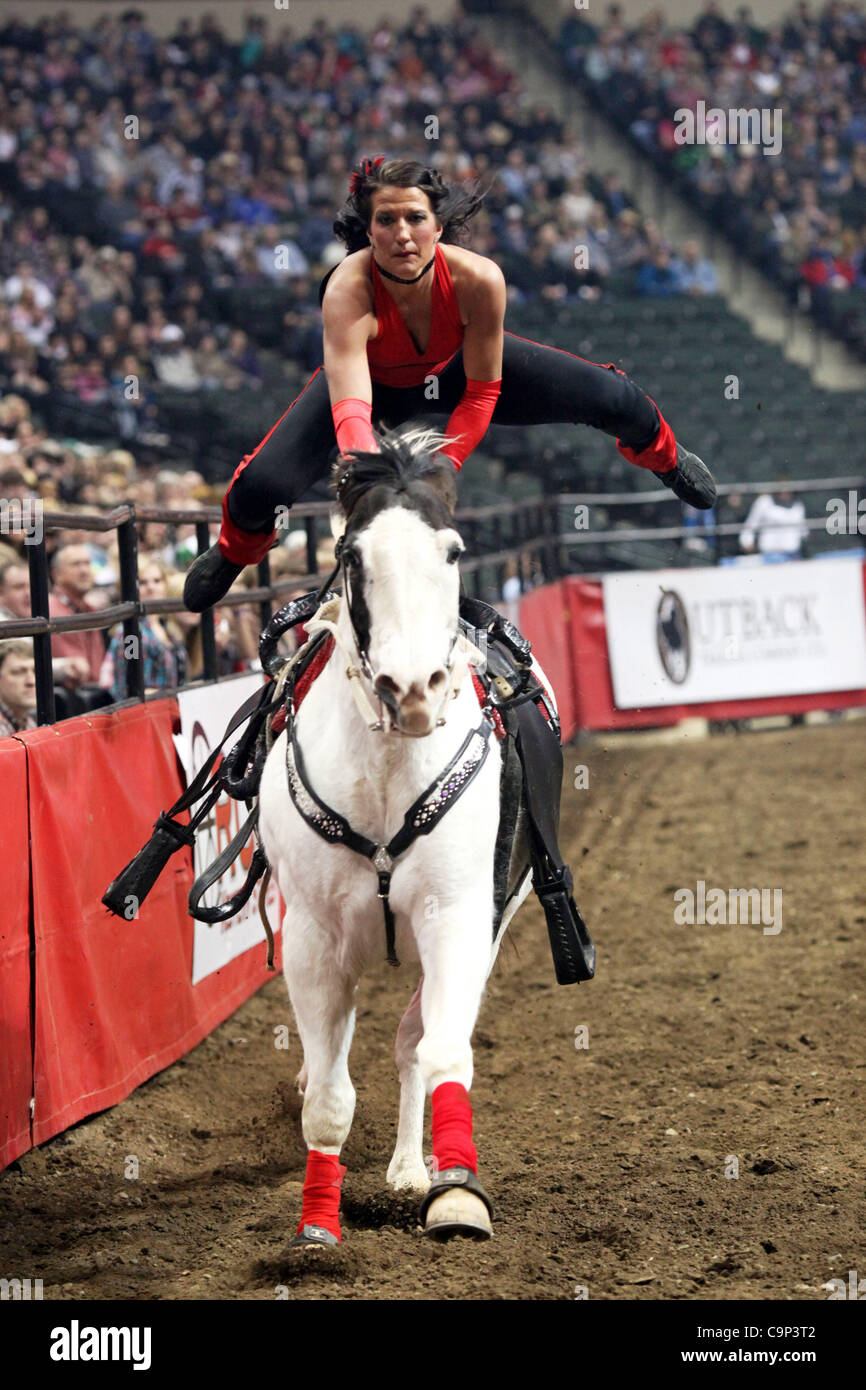 An acrobatic trick rider takes a flying position while riding a horse ...