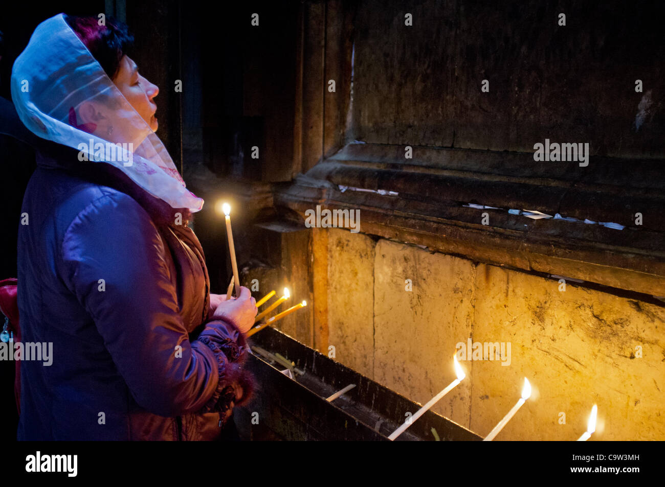 A woman prays silently holding a candle by the Edicule as thousands of ...