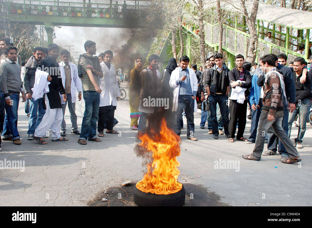 University of Health Sciences (UHS) students gather near burning tyres ...